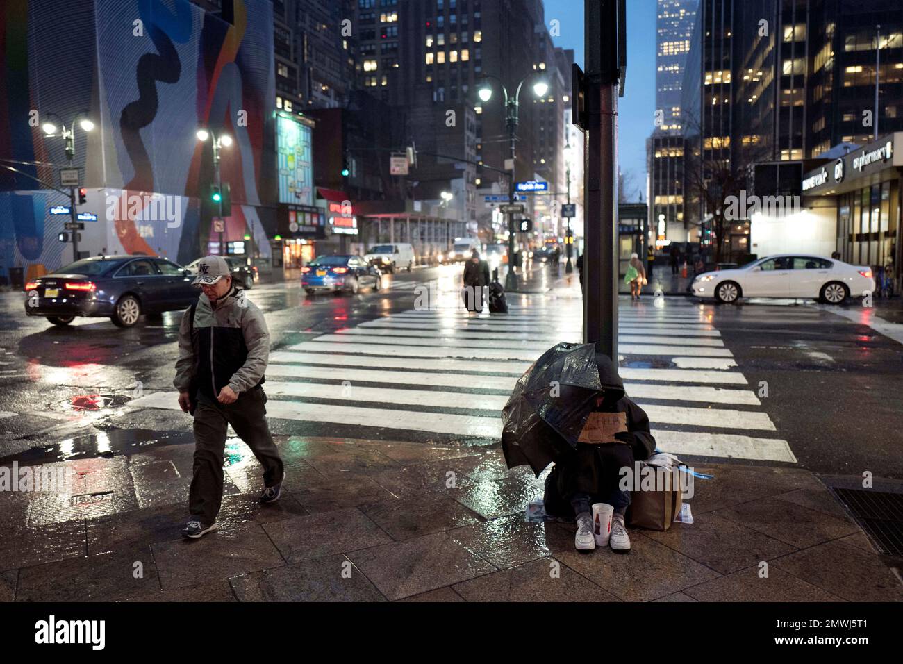 People walk by a homeless man panhandling on a New York sidewalk ...