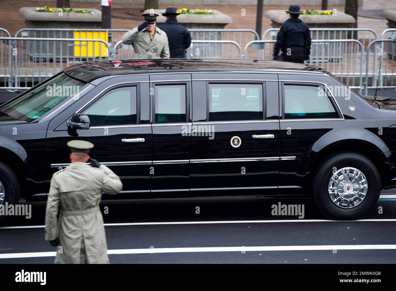 Members of the Army salute as the Presidential motorcade drives on ...