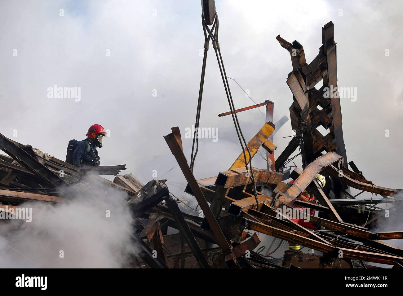 An Iranian firefighter removes debris of the Plasco building which was ...