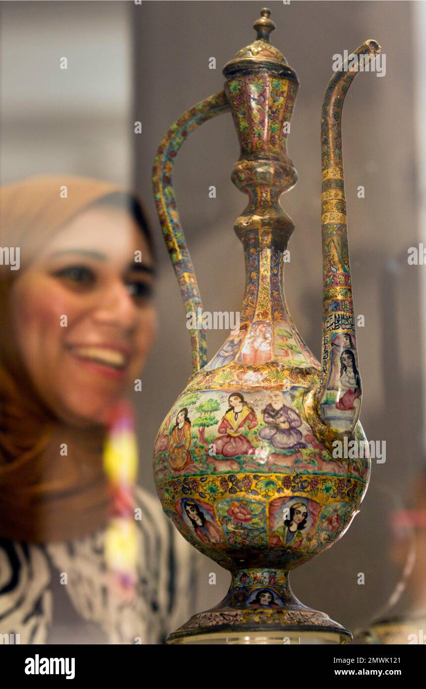 A visitor smiles as she watches an ancient ewer made of copper ...
