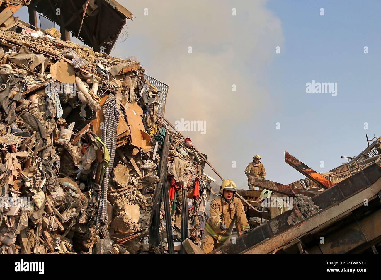 Iranian firefighters work at the scene of the collapsed Plasco building ...