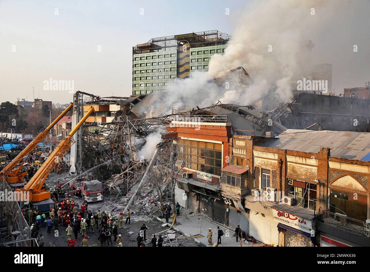 Iranian firefighters work at the scene of the collapsed Plasco building ...