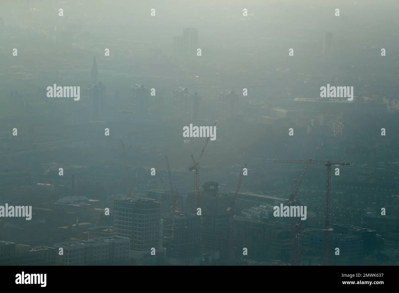 Pollution is seen over construction cranes through a window in a ...