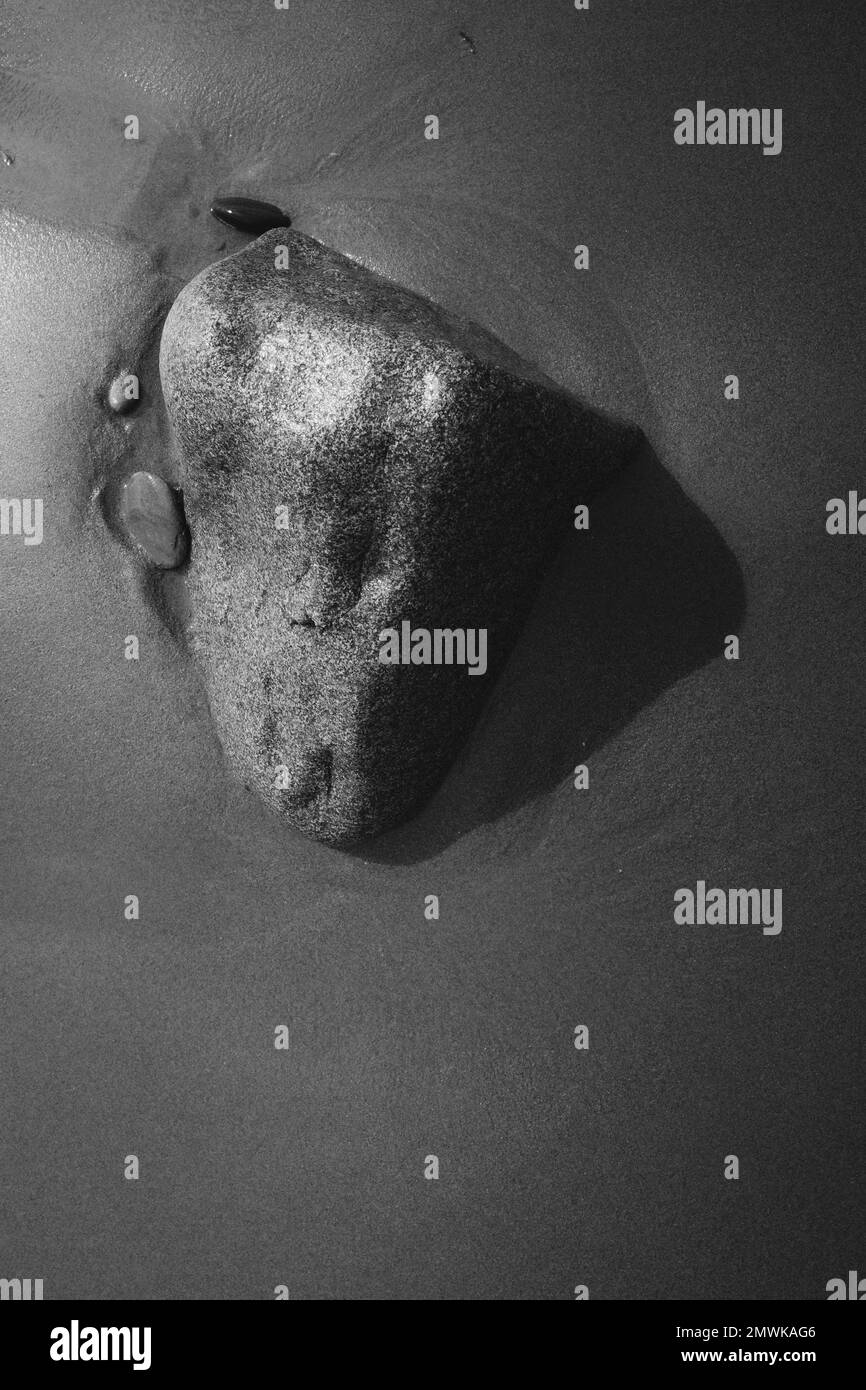 A vertical greyscale shot a rock at the beach Stock Photo - Alamy