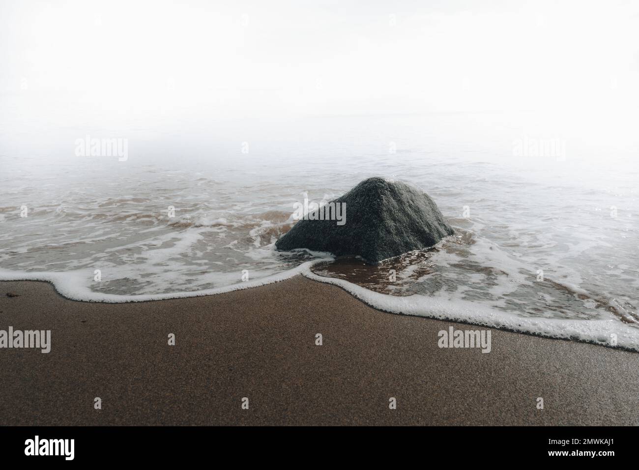 A big rock at the beach on a gloomy day Stock Photo - Alamy