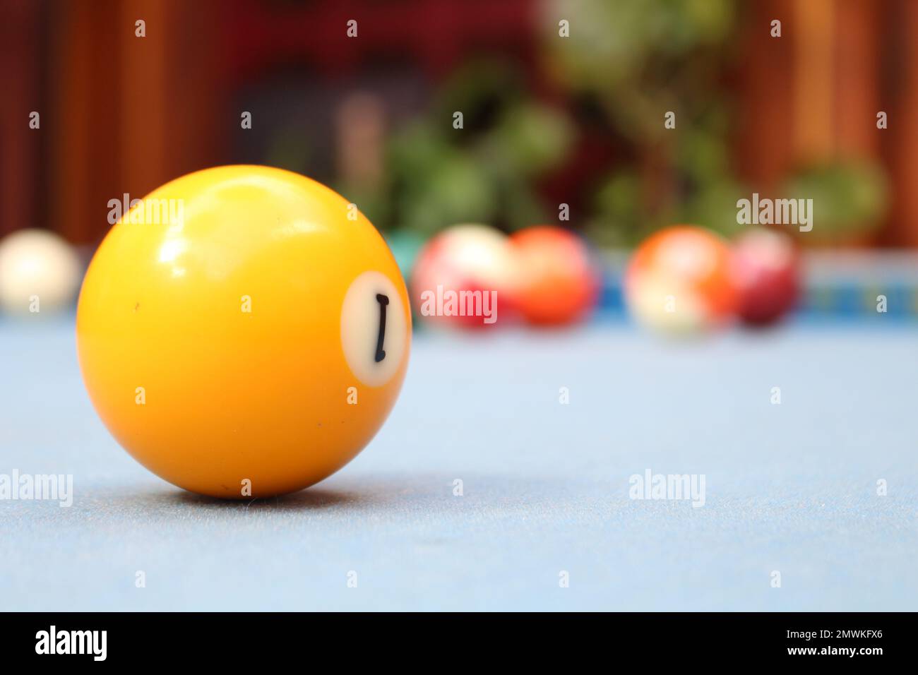 Yellow Pool ball sitting on a table with other balls in the background ...