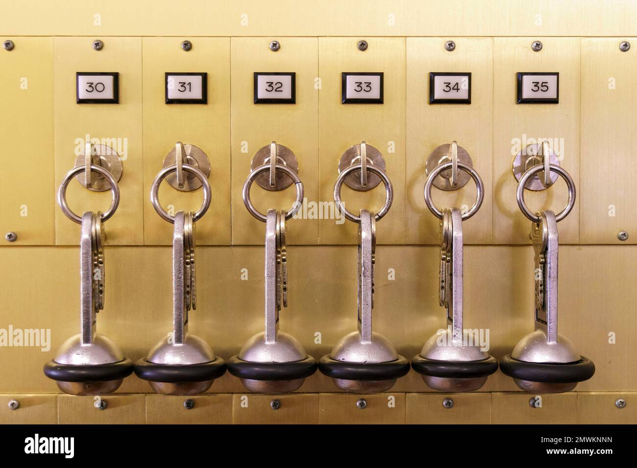 A row of old-fashioned metal hotel keys hang below room numbers Stock ...