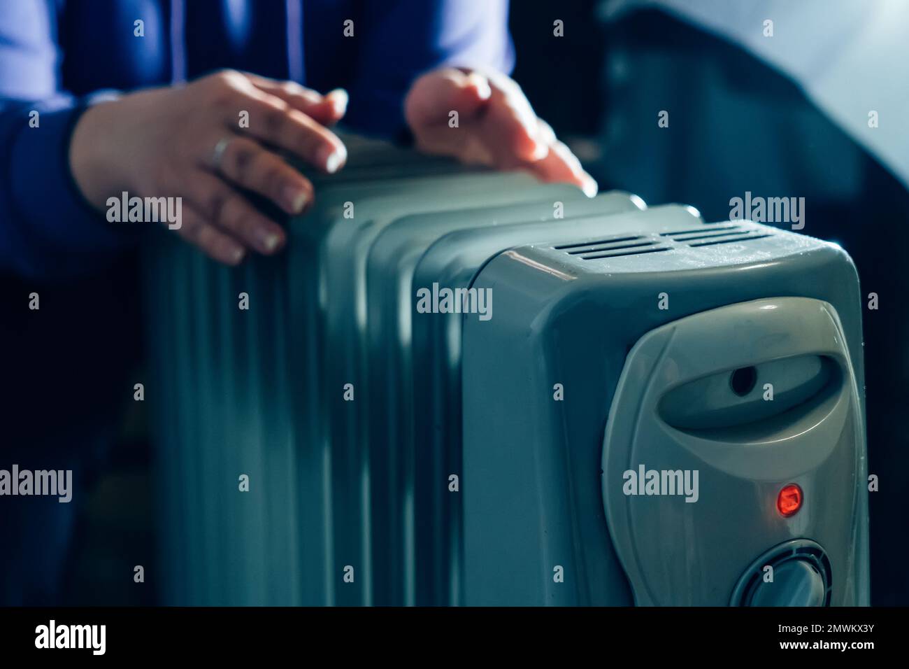 Female hands warming on oil heater at home close up. Cold winter with ...