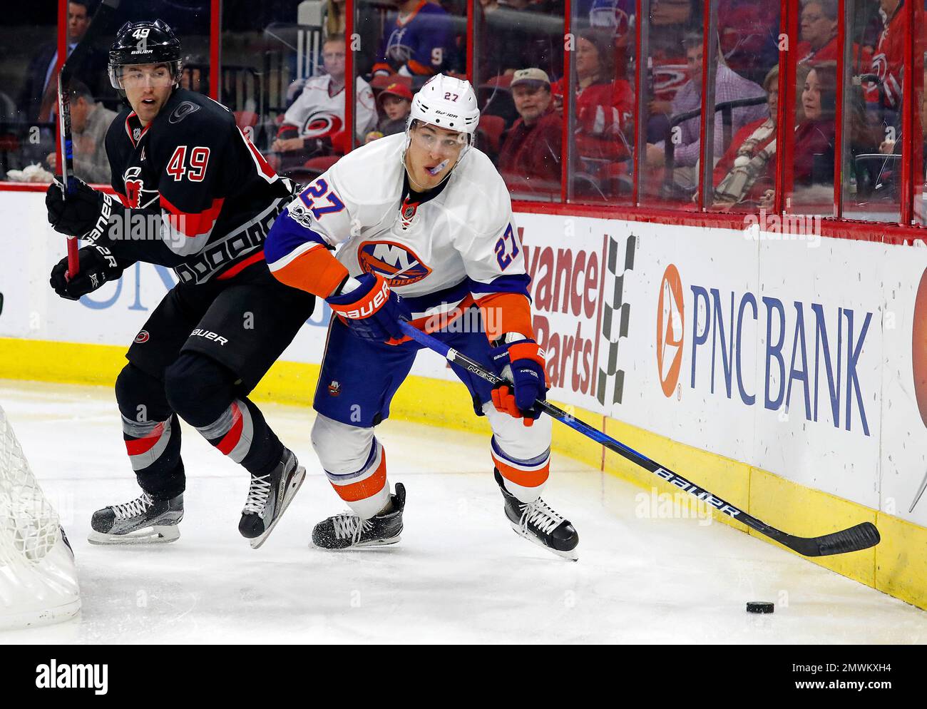 New York Islanders' Anders Lee (27) moves the puck behind Carolina ...