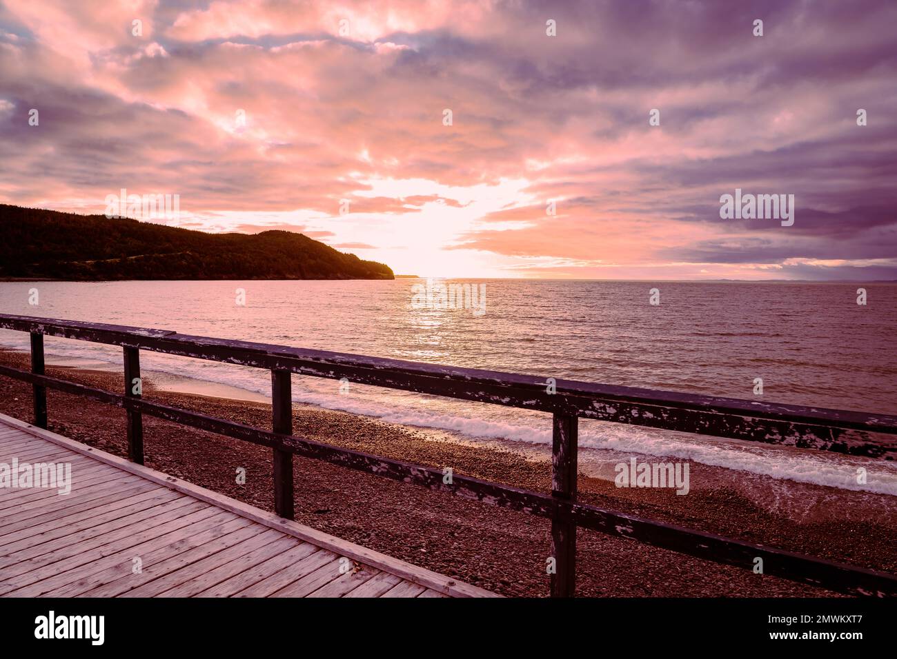 Wooden boardwalk with handrail overlooking the Atlantic Ocean during ...
