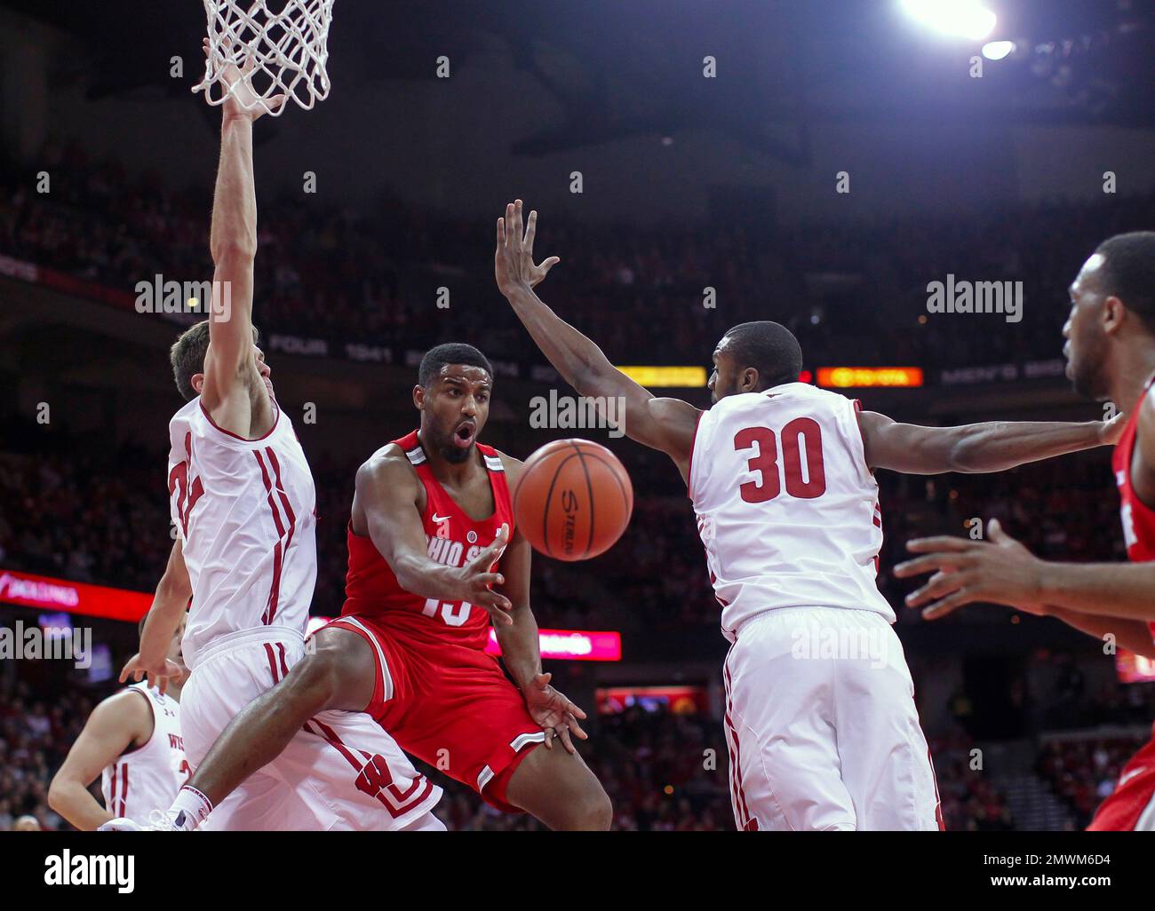Ohio State's JaQuan Lyle, center, passes as Wisconsin's Ethan Happ ...