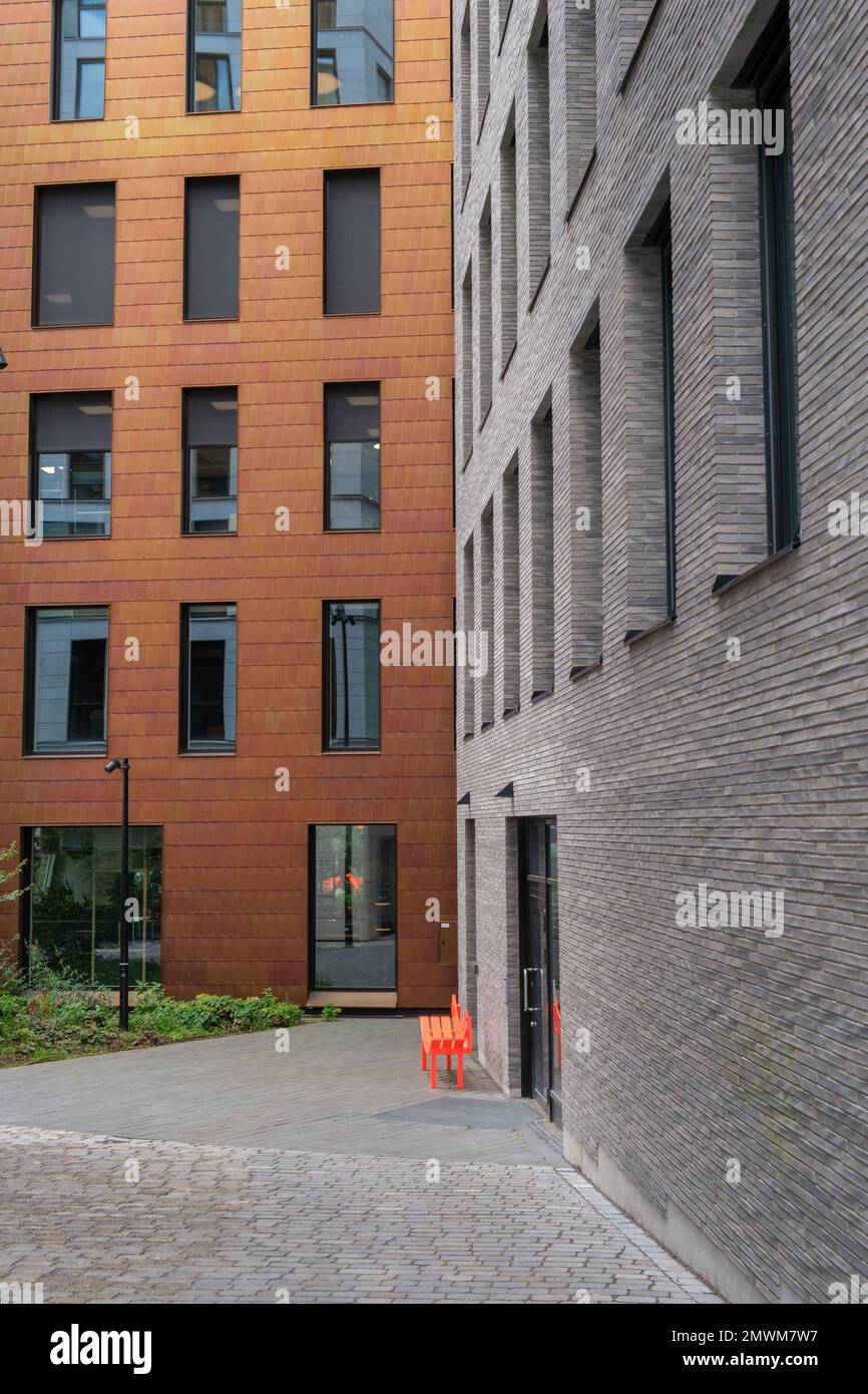 A vertical closeup shot of modern office buildings and an orange bench ...