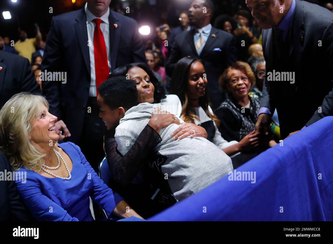First lady Michelle Obama hugs a young boy as she sit in the front row ...