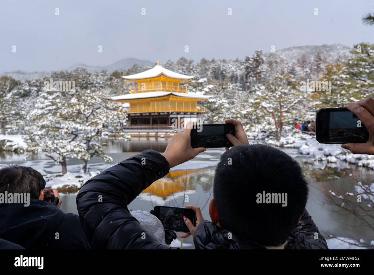 Crowd of people taking pictures of snowy Kinkaku-ji Temple in winter ...