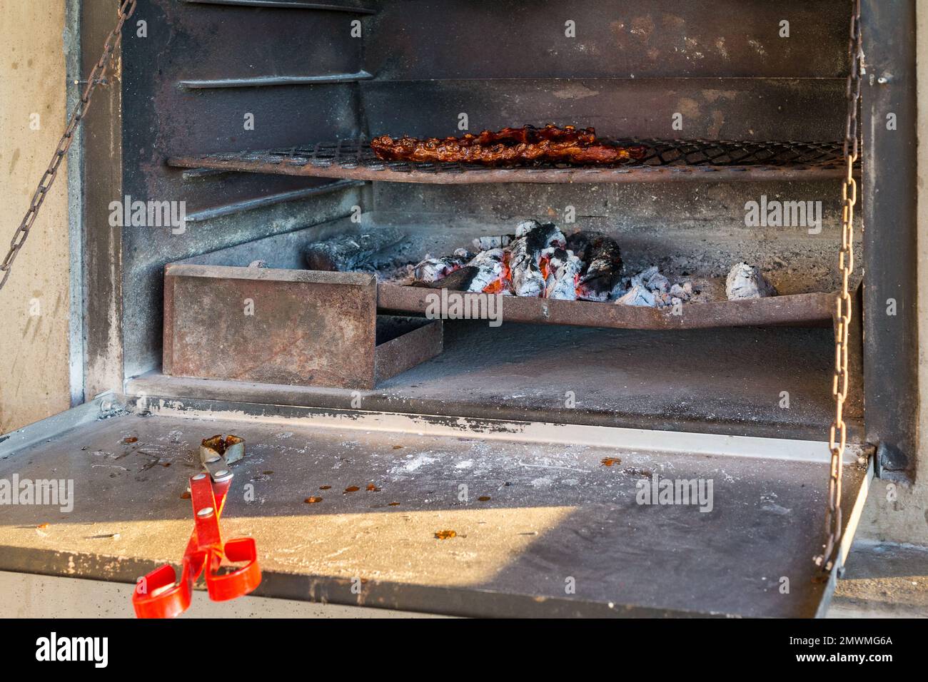 pork ribs, meat, food on a metal grid in a fireplace above burning ...