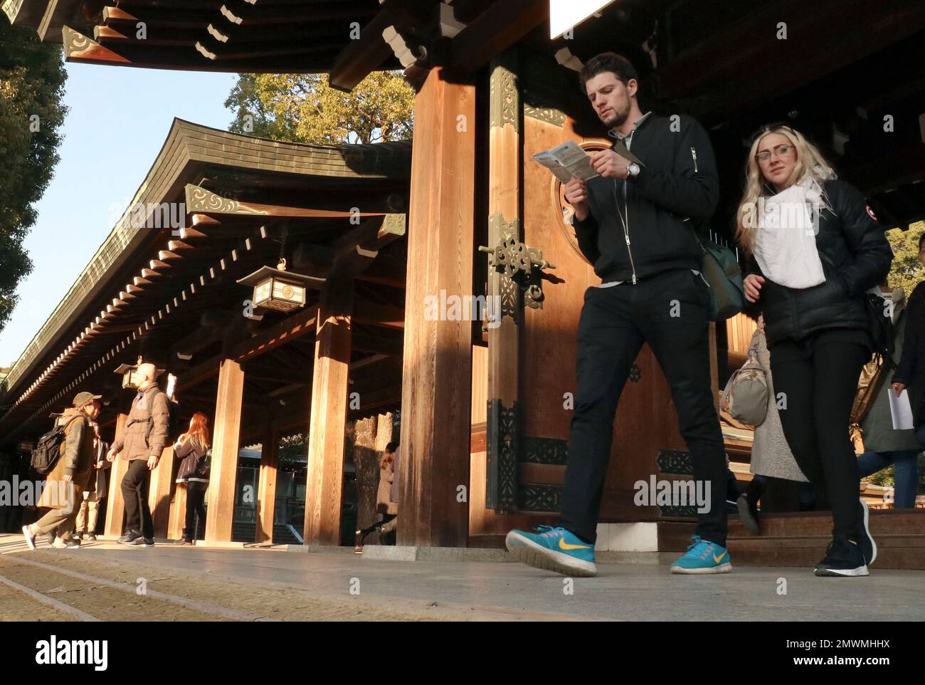 A tourist couple checking a map walks through a shrine gate at Meiji ...
