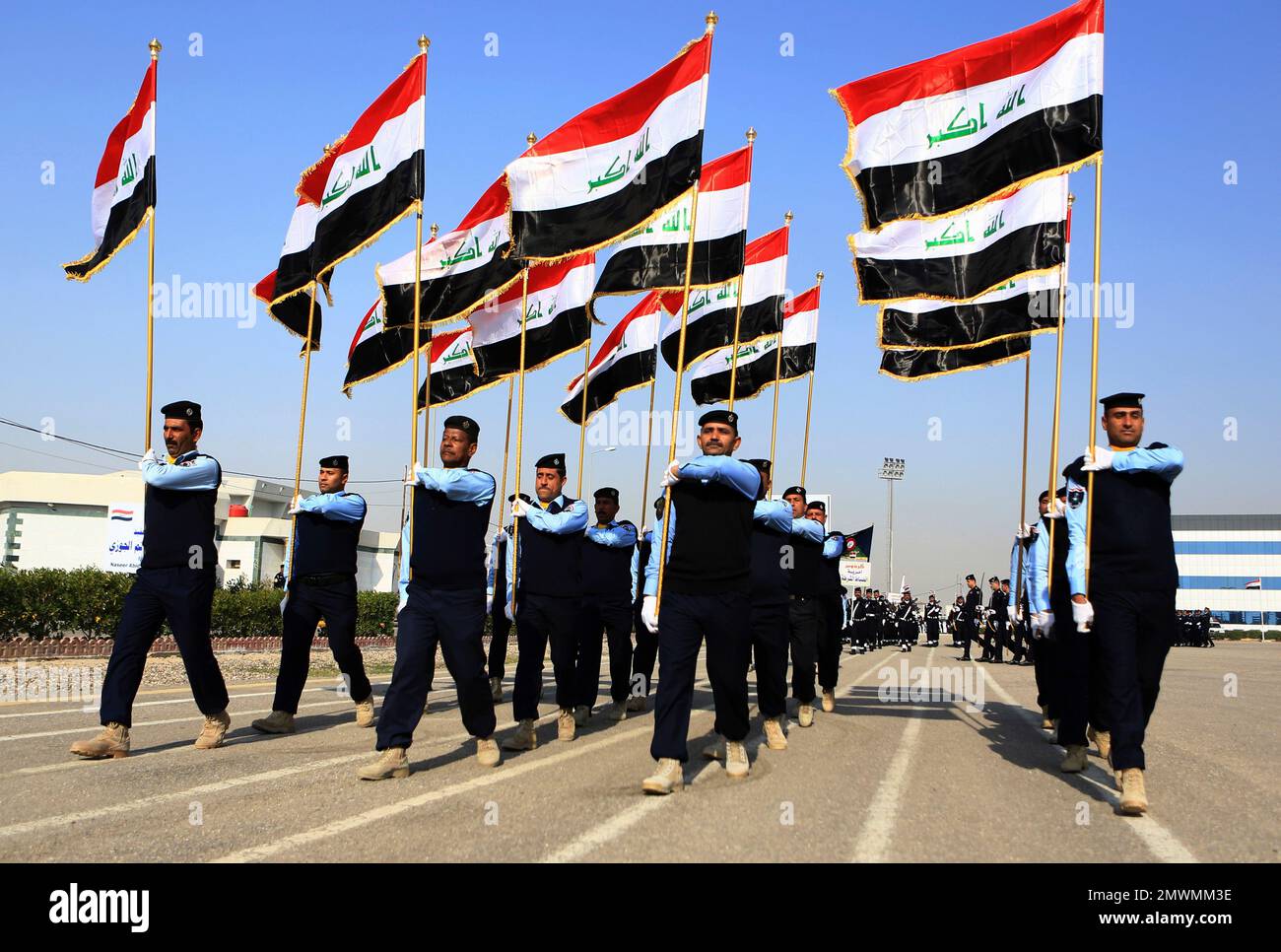 Iraqi policemen march holding national flags during a ceremony marking ...