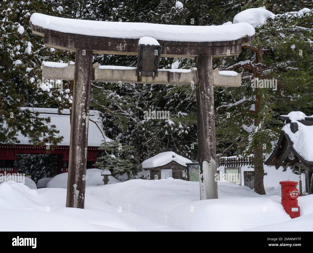 A torii gate to a Shinto shrine with deep snow at the base of Mount ...