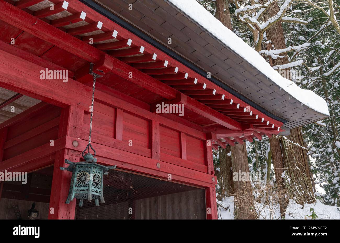 A lantern hanging from a gate to a Shinto shrine with deep snow at the ...
