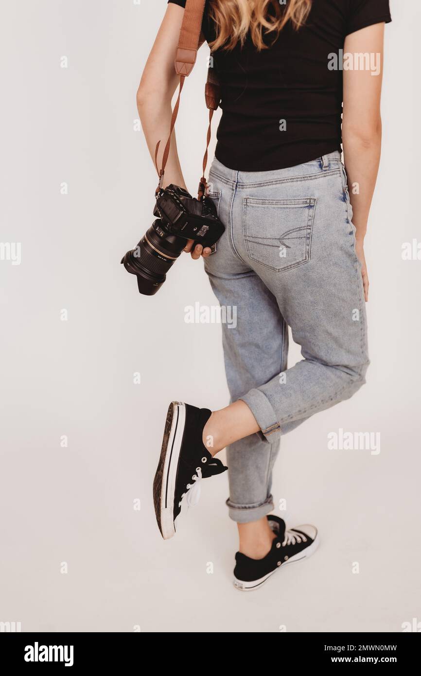 A vertical back view of a female photographer walking with a camera ...