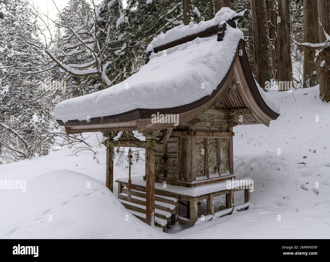 A wooden Shinto shrine building with deep snow at the base of Mount ...