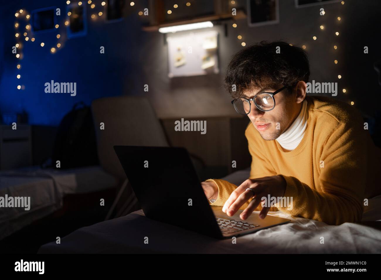 Happy young student wearing glasses working, learning online late at ...