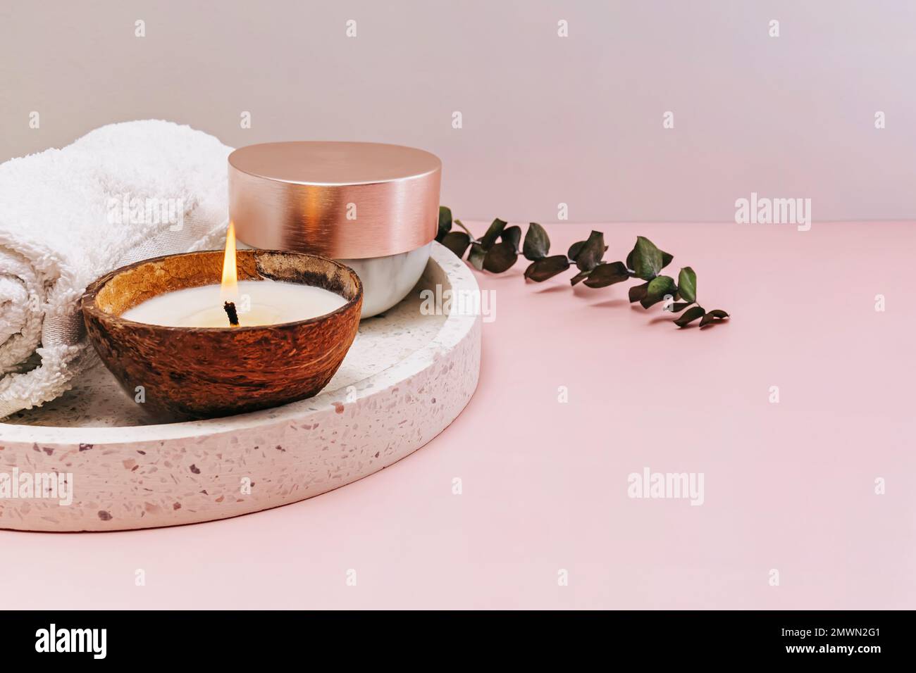 Still life body and face care items and candle in coconut shell on pink ...
