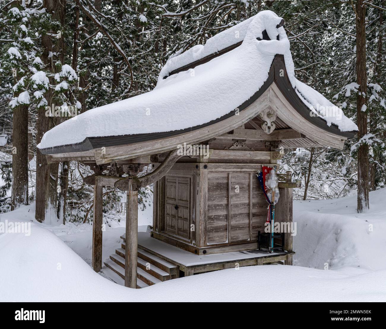 A wooden Shinto shrine building with deep snow at the base of Mount ...