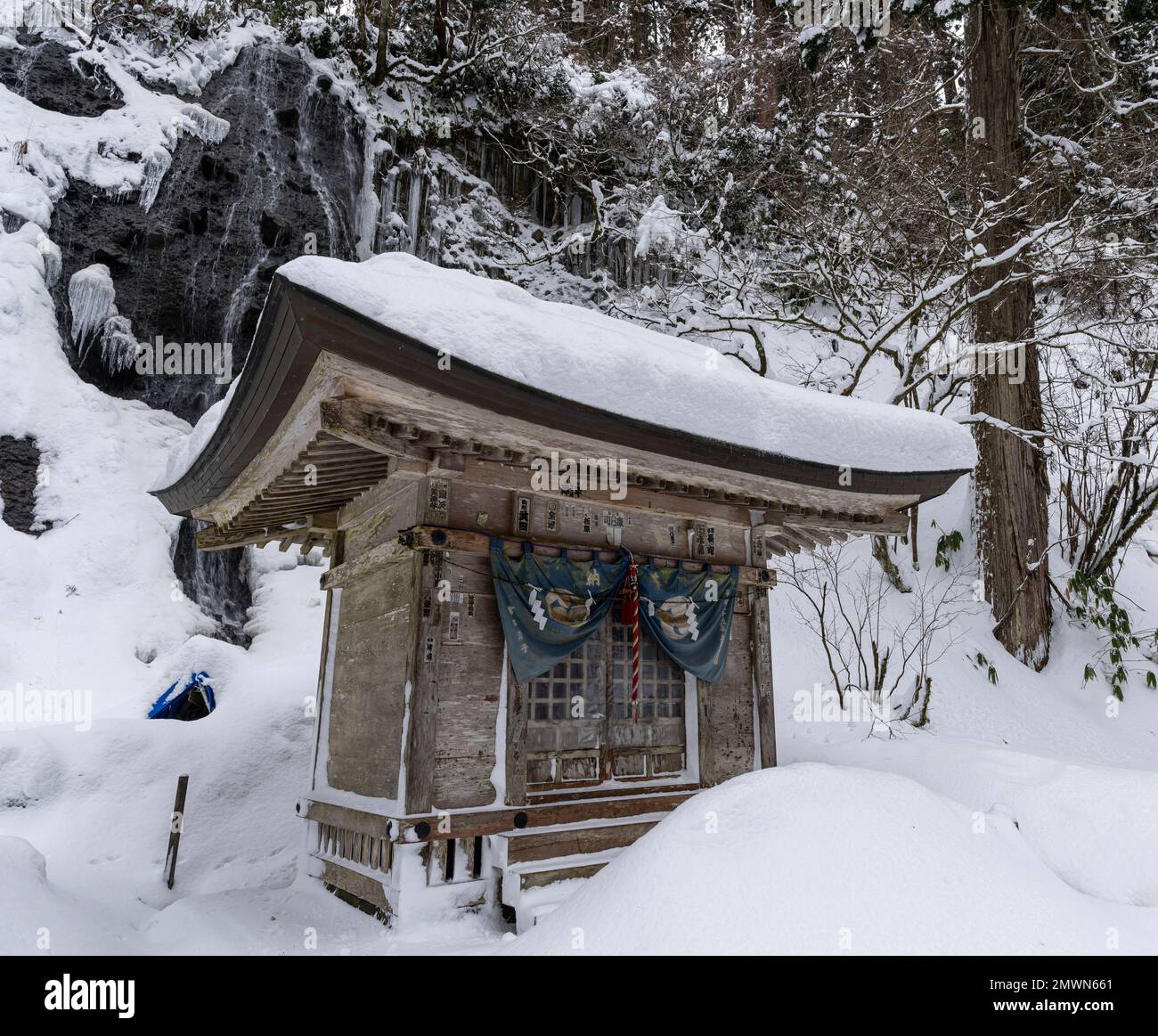 A wooden Shinto shrine building with deep snow in front of Suganotaki ...