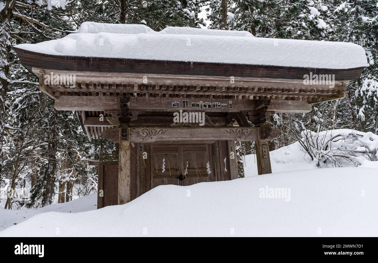 A wooden Shinto shrine building with deep snow at the base of Mount ...