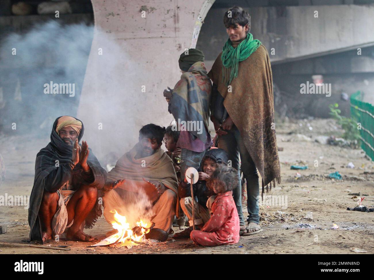 Homeless Indians warm themselves by a bonfire under a flyover in Jammu ...