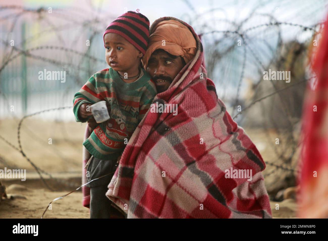 Homeless Indians sit wrapped in warm clothes under a flyover in Jammu ...