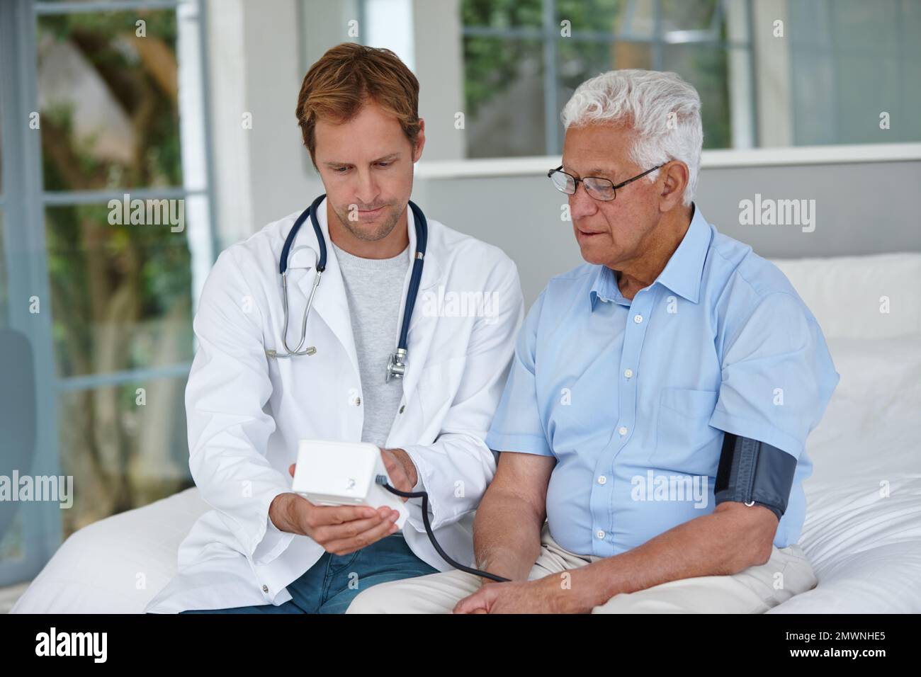 Making sure his patients blood pressure is under control. a male doctor ...