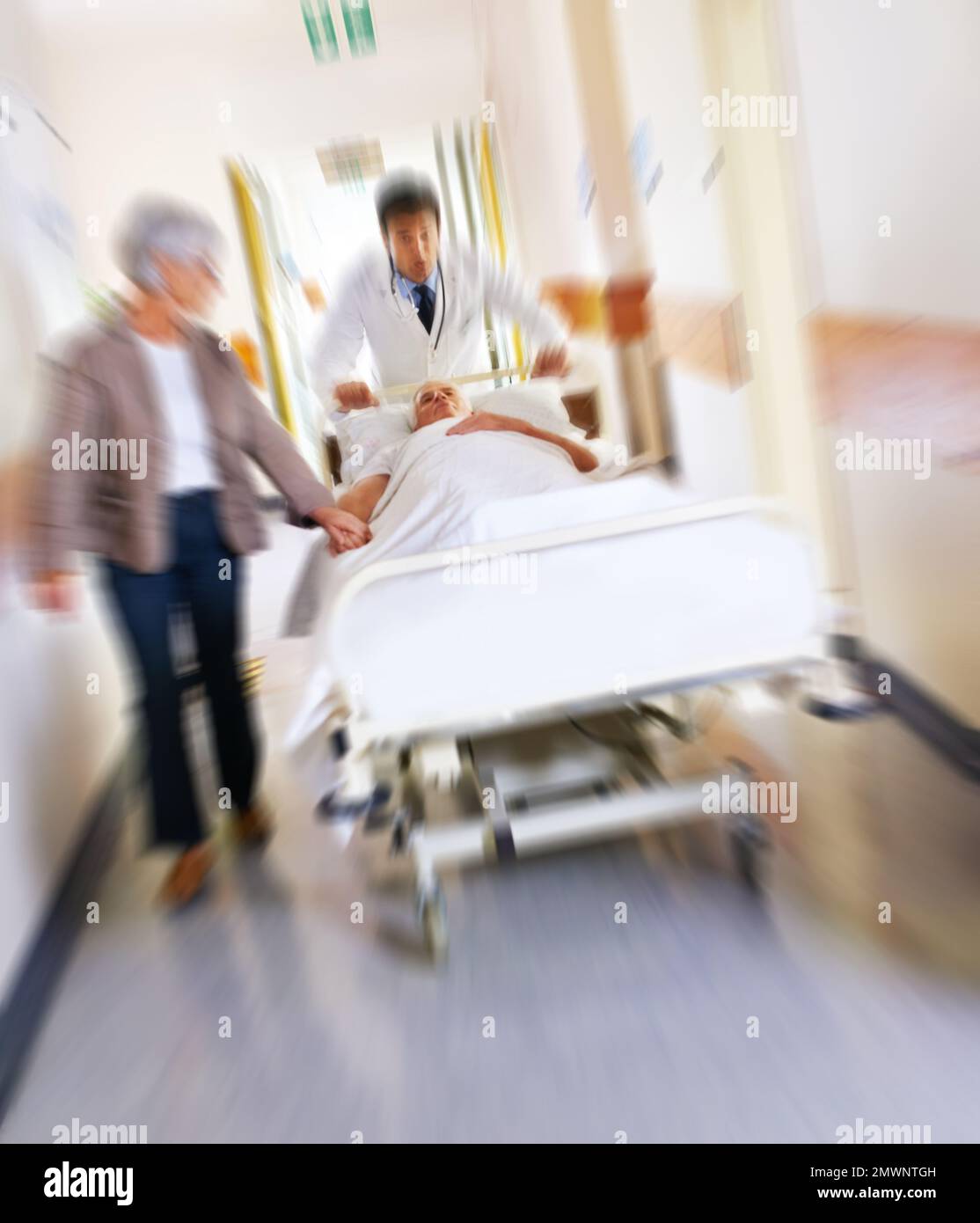 Emergency. a sick man on a bed being wheeled at speed through a ...