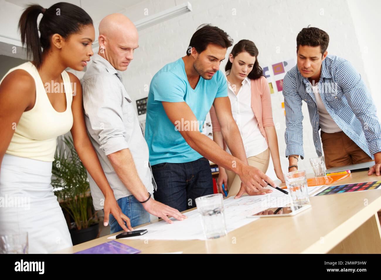 Perfecting the plan. A group of designers gathered together around an ...