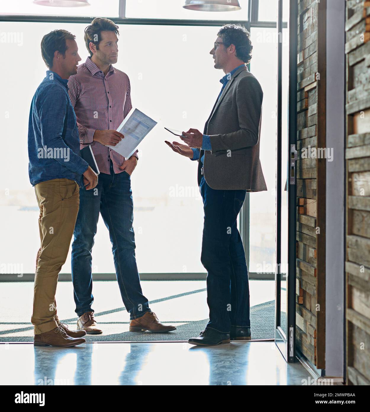 Business communication. male coworkers talking while standing in front ...