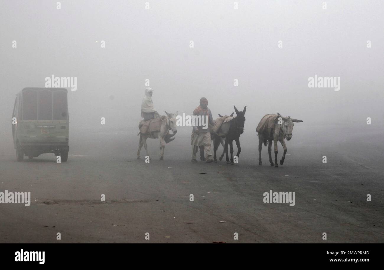Pakistani laborers make their way to work on a foggy day in Lahore ...