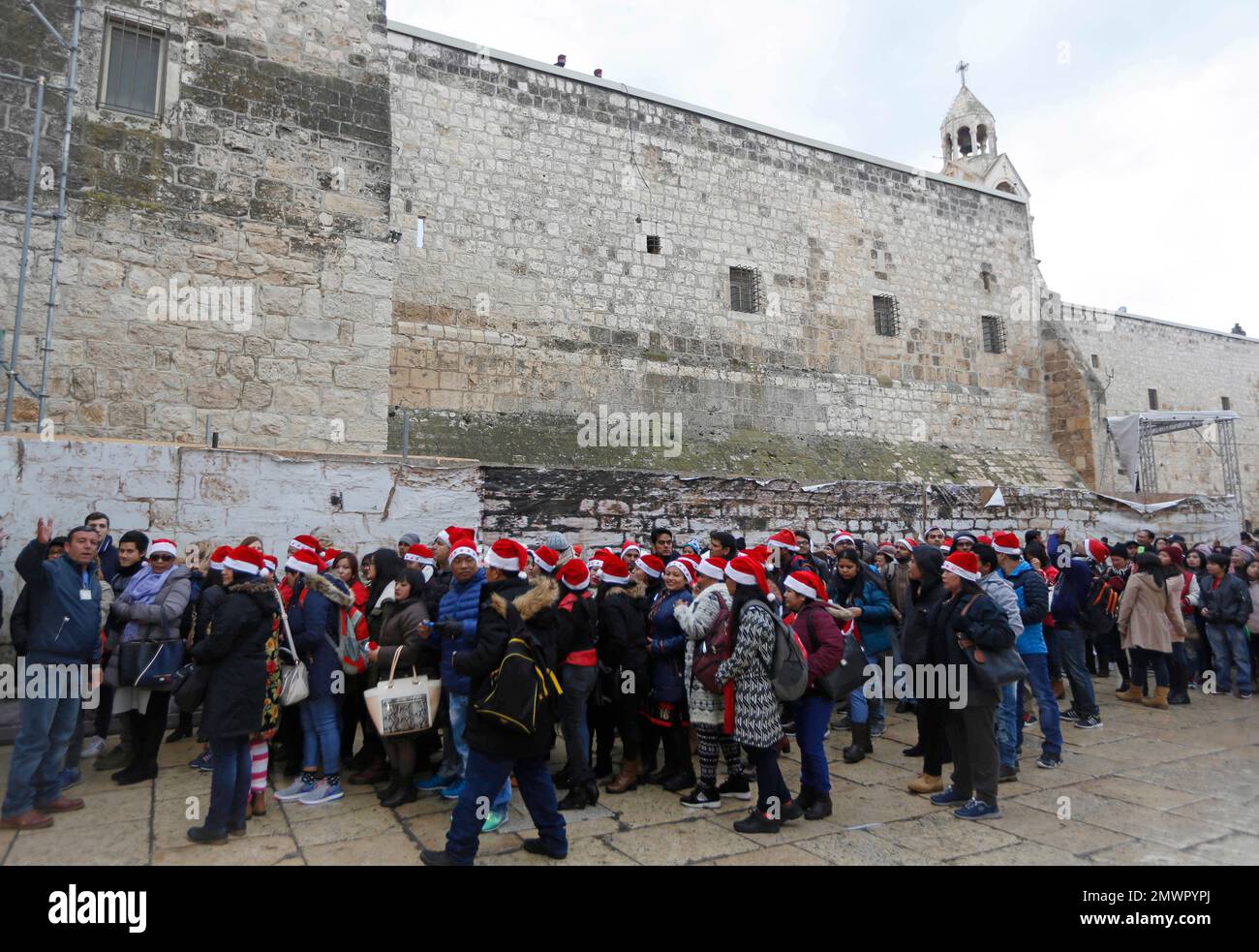 Christian pilgrims wearing red Santa hats wait in line to enter the ...