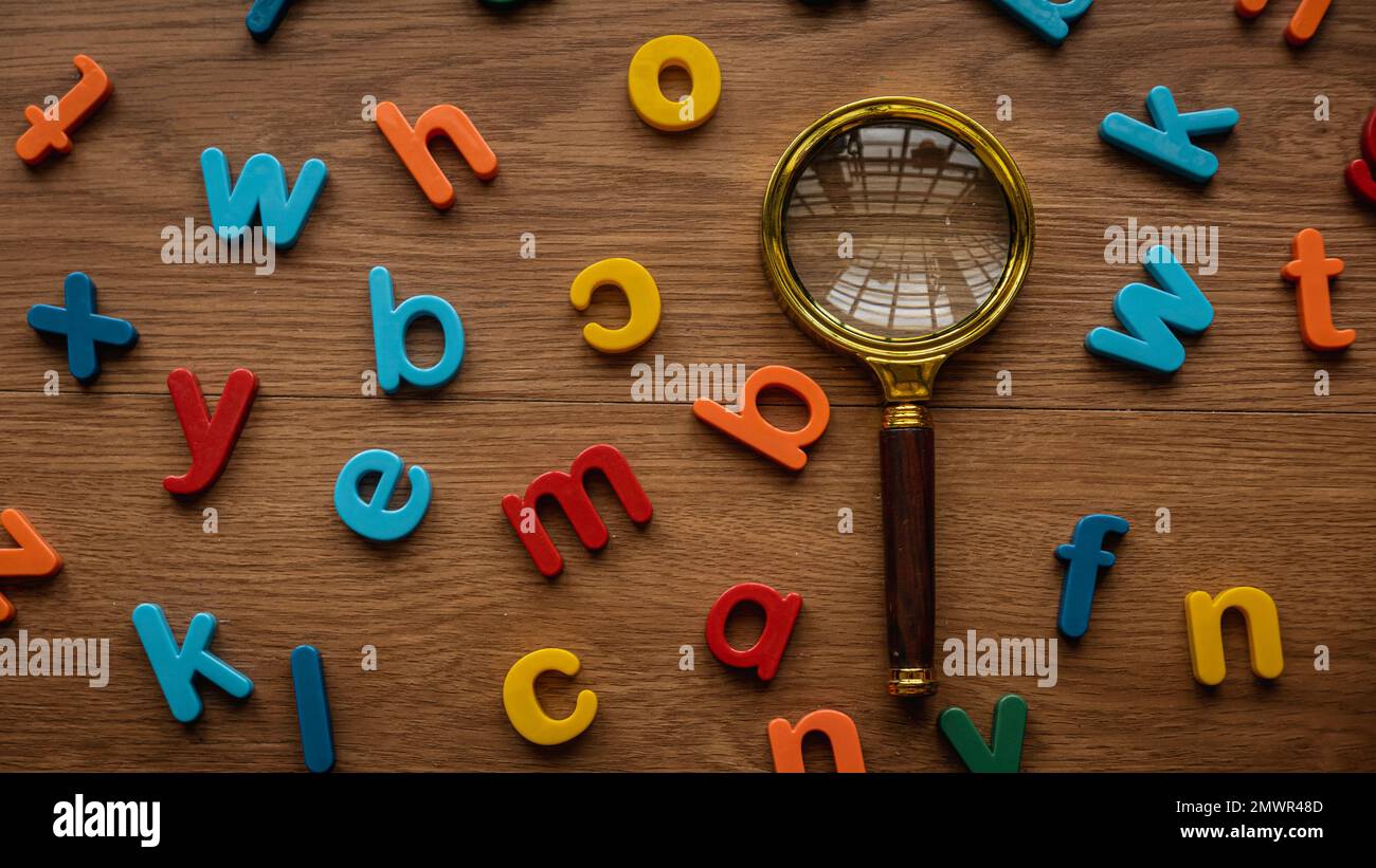 Scattered colorful alphabet with a magnifying glasses. Learning and ...