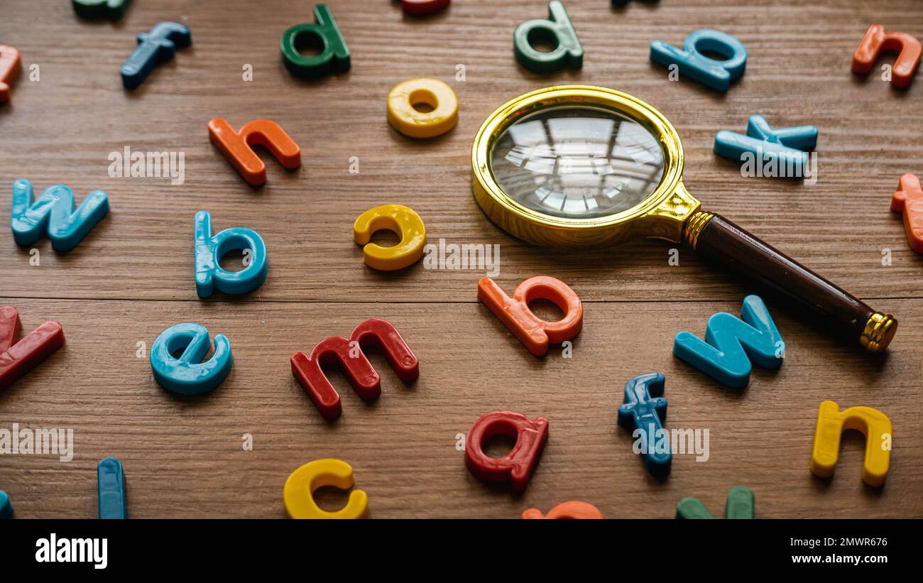 Scattered colorful alphabet with a magnifying glasses. Learning and ...