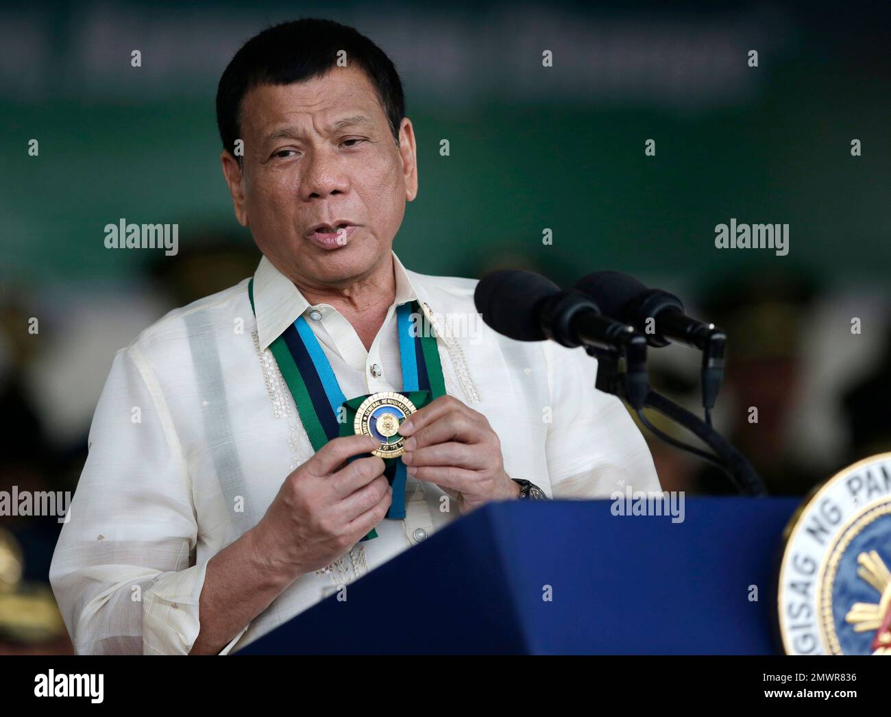 Philippine President Rodrigo Duterte shows a medal during his speech to ...