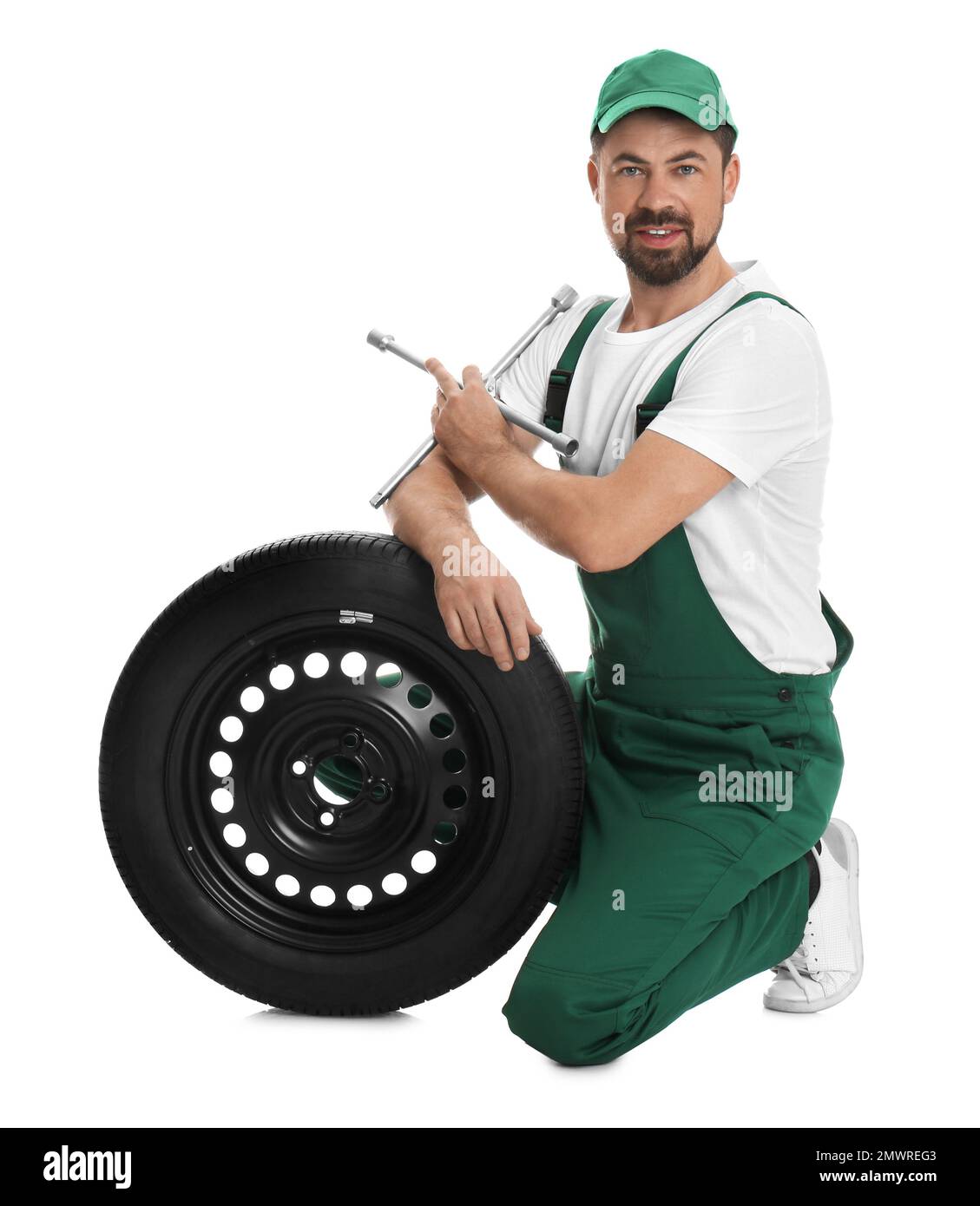 Professional auto mechanic with wheel and lug wrench on white ...