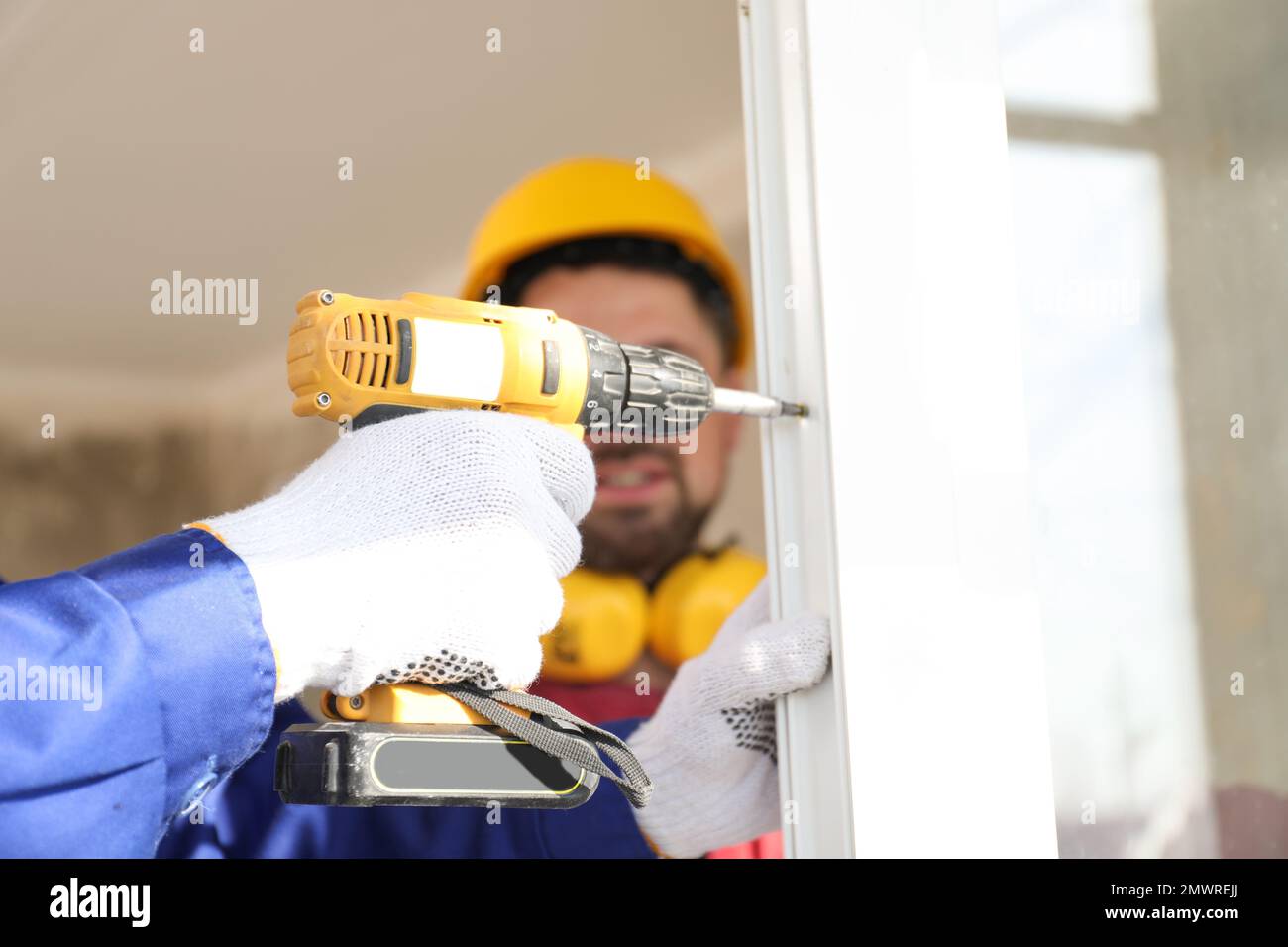 Workers using electric screwdriver for window installation indoors ...