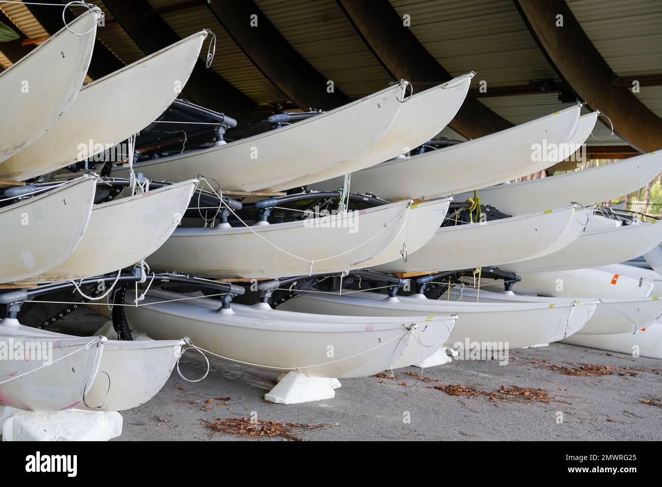 hulls of school sailboats racked one above another on two levels in a ...