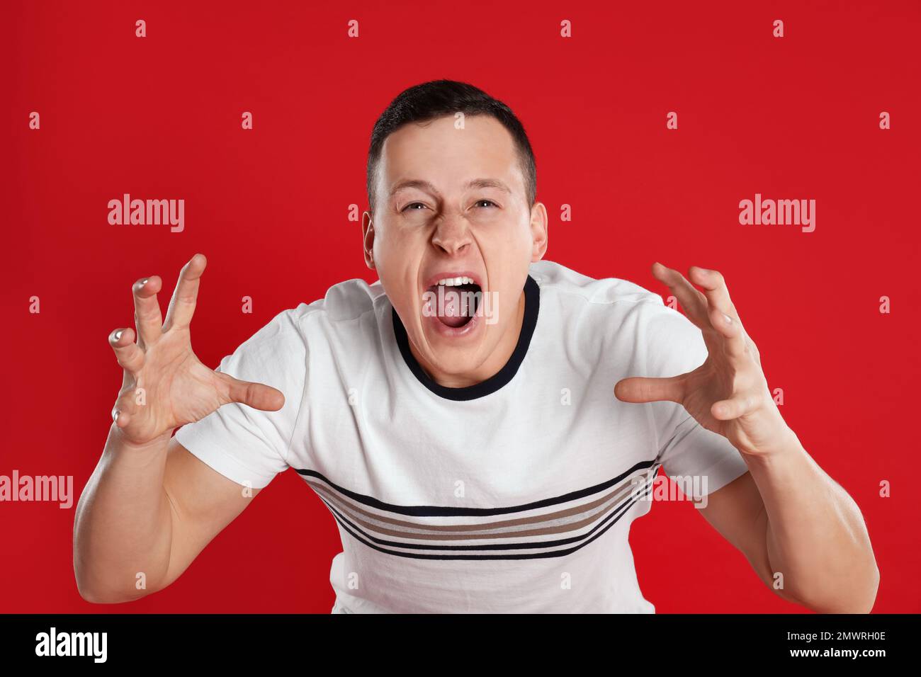 Emotional young man posing on red background Stock Photo - Alamy