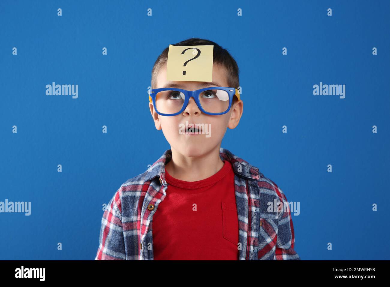 Emotional little boy with question mark on blue background Stock Photo ...