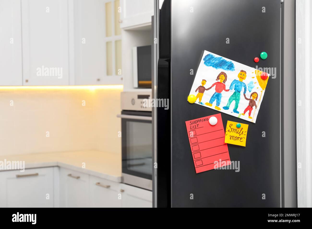 Modern refrigerator with child's drawing, notes and magnets in kitchen ...
