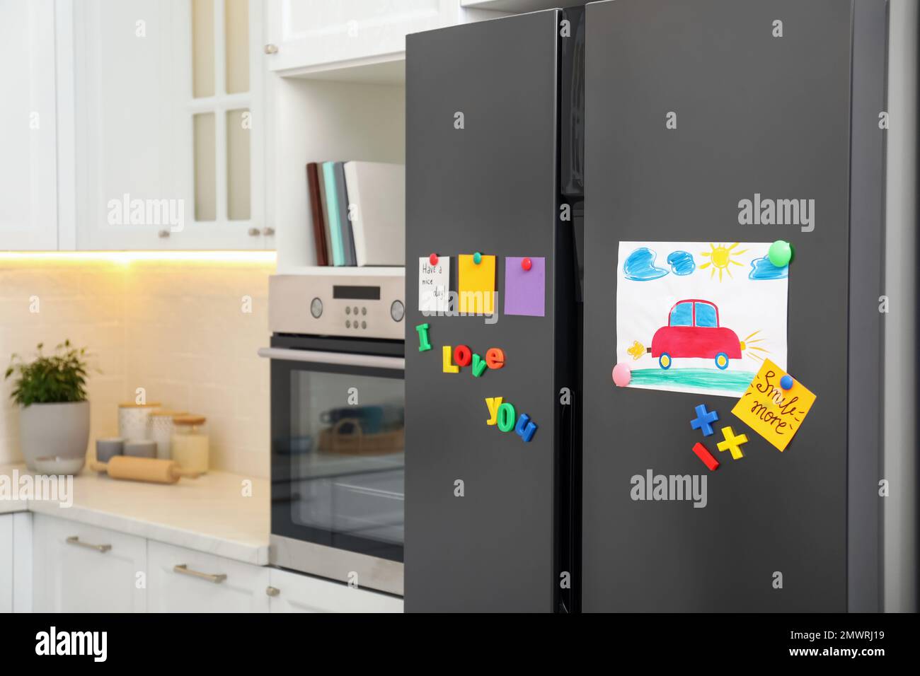 Modern refrigerator with child's drawing, notes and magnets in kitchen ...