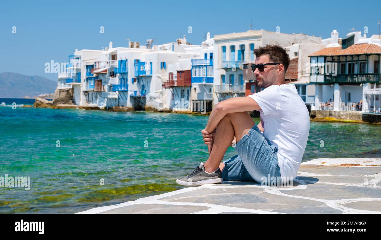 Young men visit Mykonos Greek village in Greece, with colorful streets ...