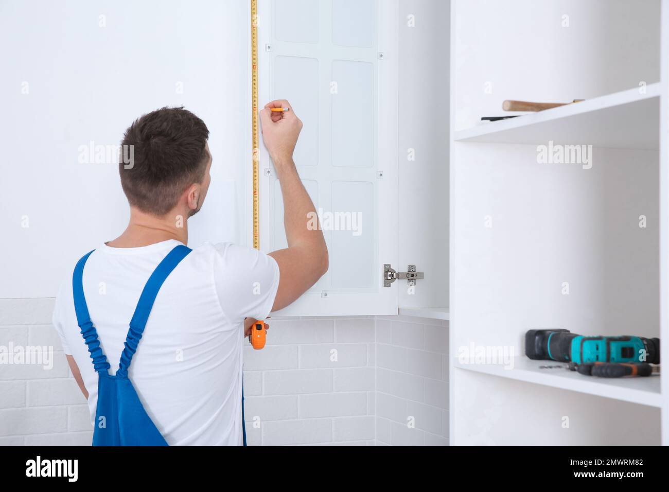 Worker measuring newly installed kitchen furniture indoors Stock Photo ...